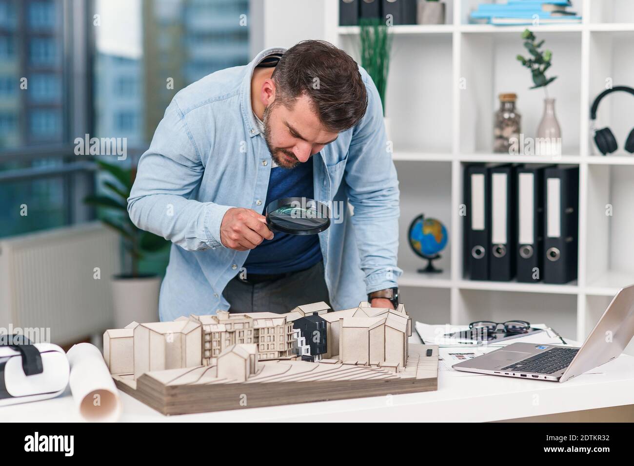 Architect inspector examines a house model using a magnifying glass ...