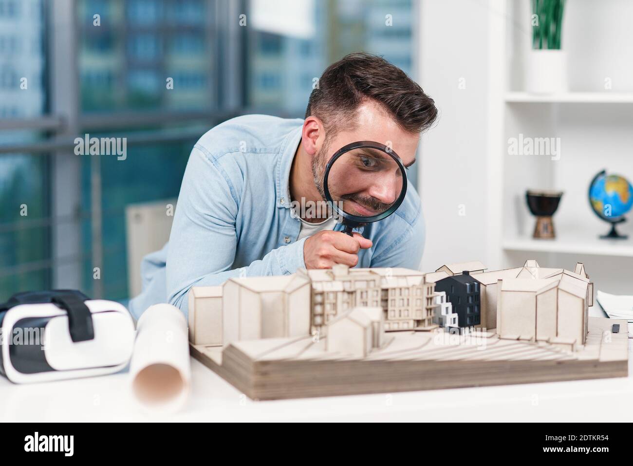 Funny picture of architect looks through magnifying glass to a house ...