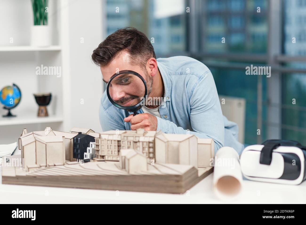 Funny picture of architect looks through magnifying glass to a house ...