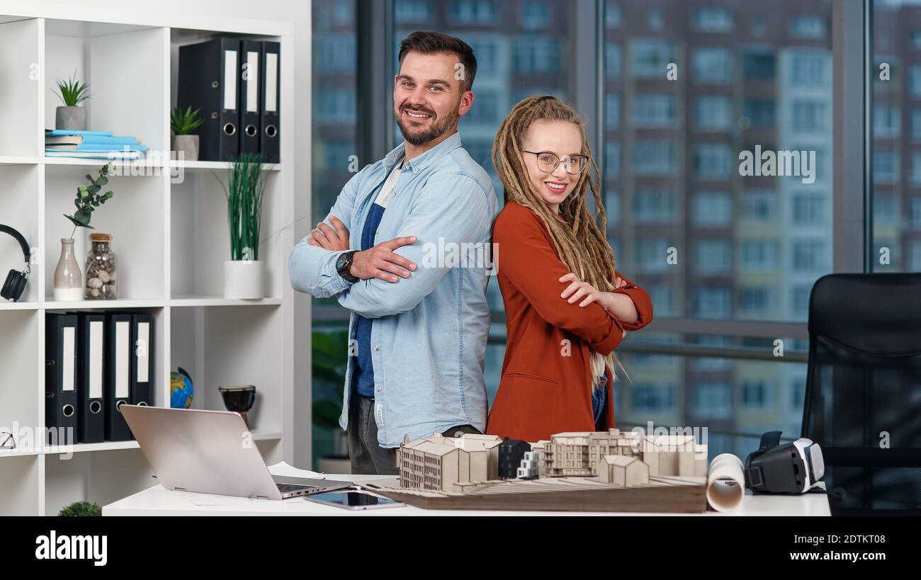 Professional architect stands back to back with pretty female colleague ...