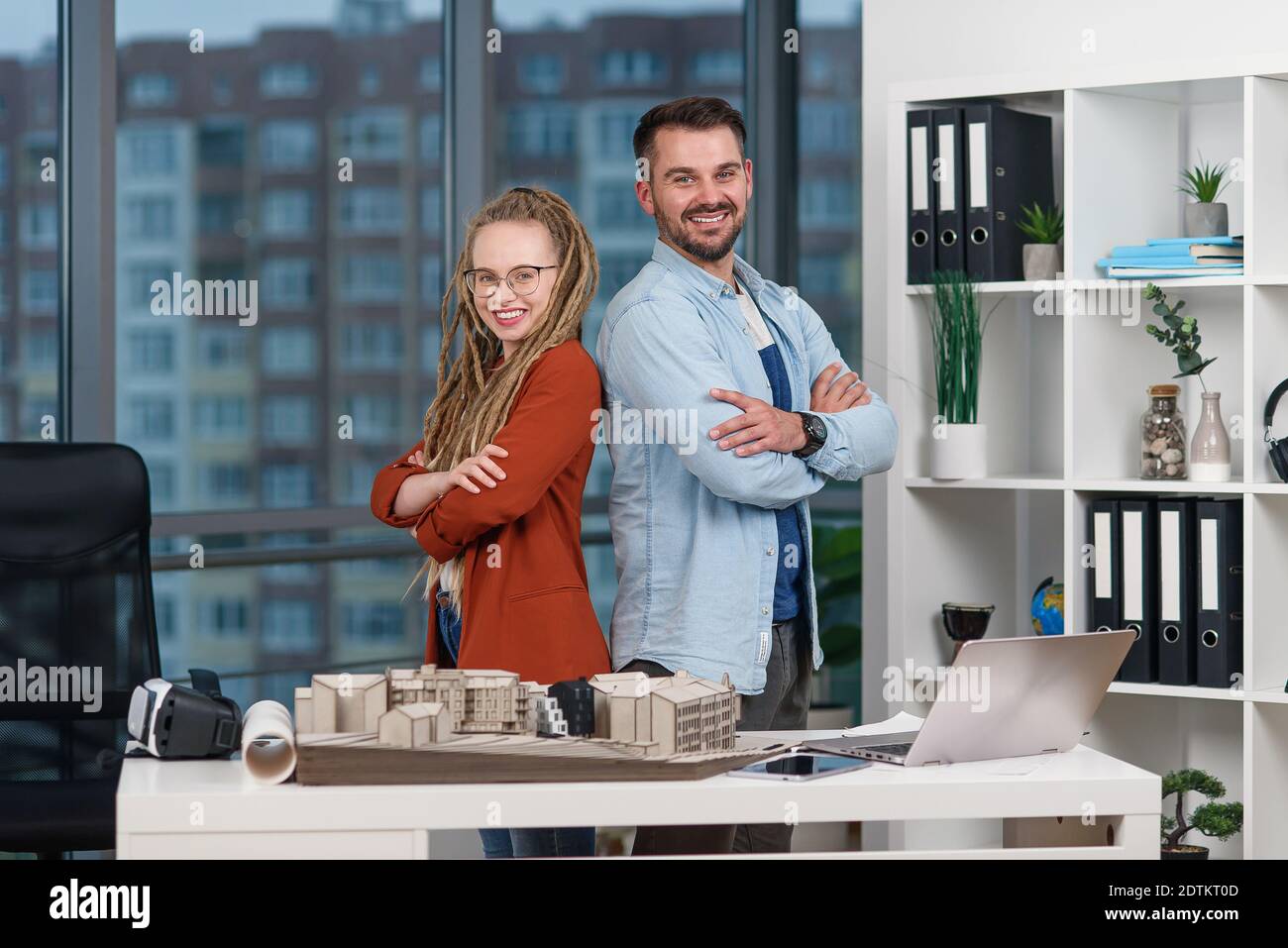 Professional architect stands back to back with pretty female colleague ...