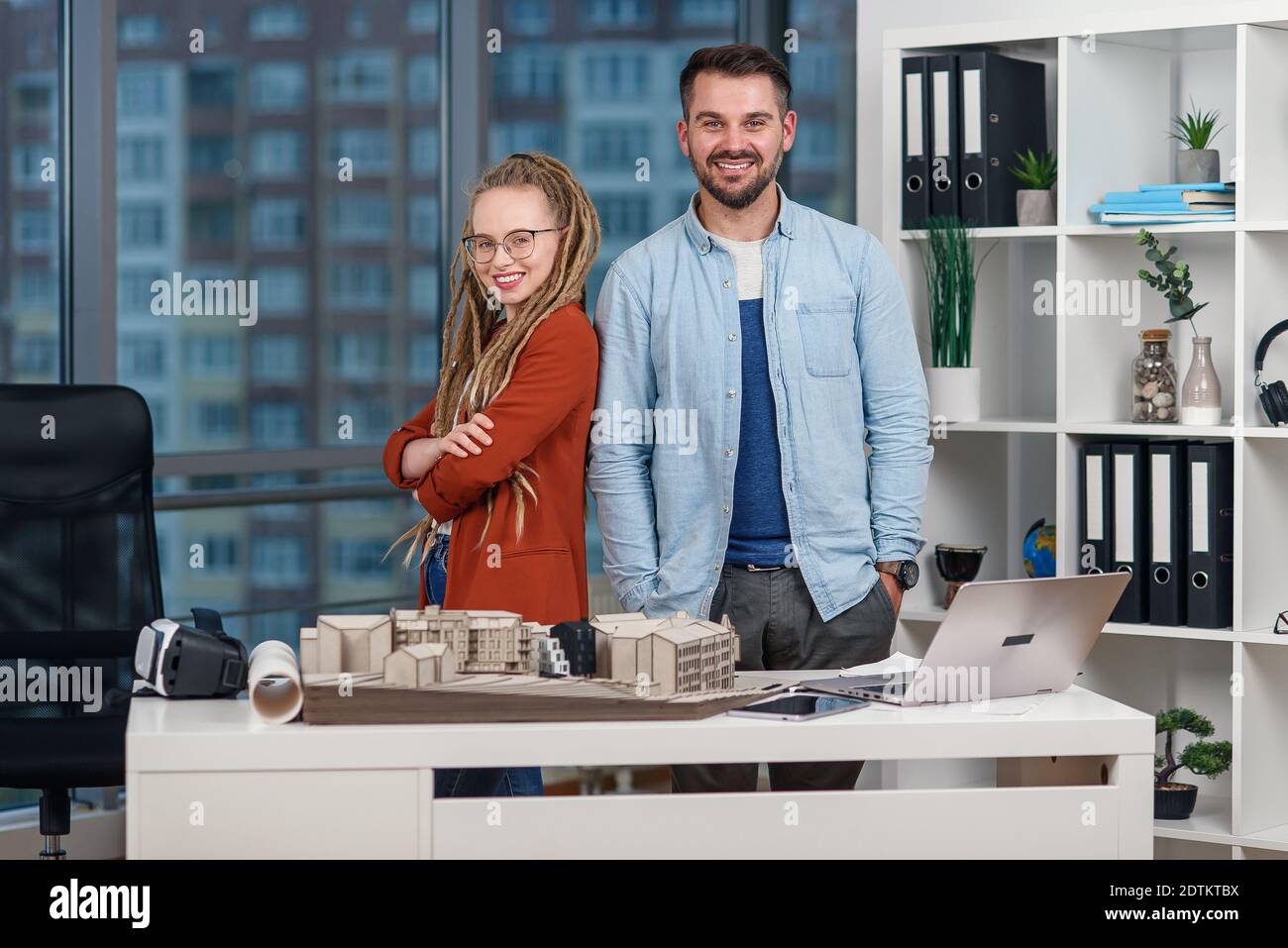 Professional architect stands back to back with pretty female colleague ...