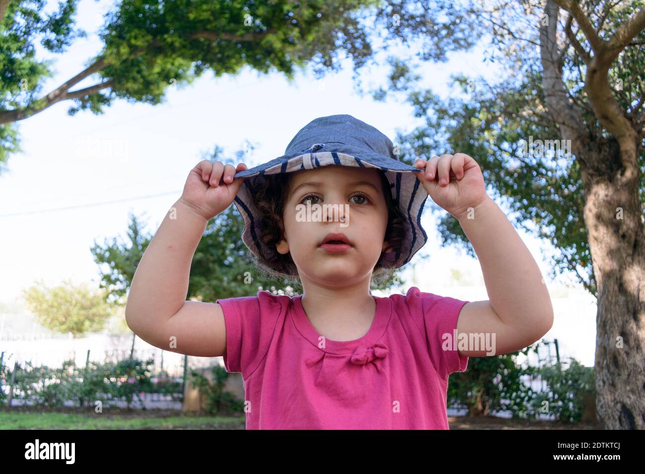 Toddler with hat of head plays outdoors Stock Photo - Alamy