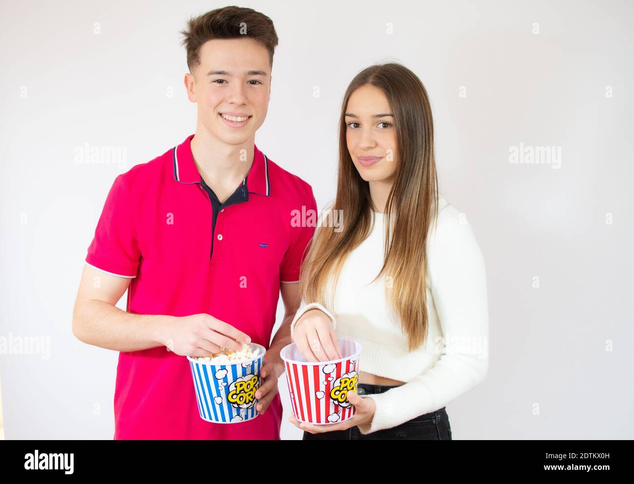 Young couple holding buckets of popcorn over white background Stock ...