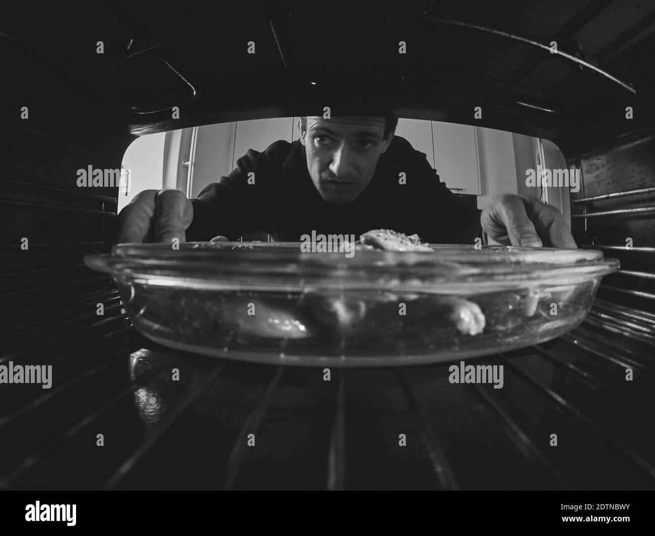 Portrait Of Young Man Sitting Putting Food In The Oven Stock Photo - Alamy