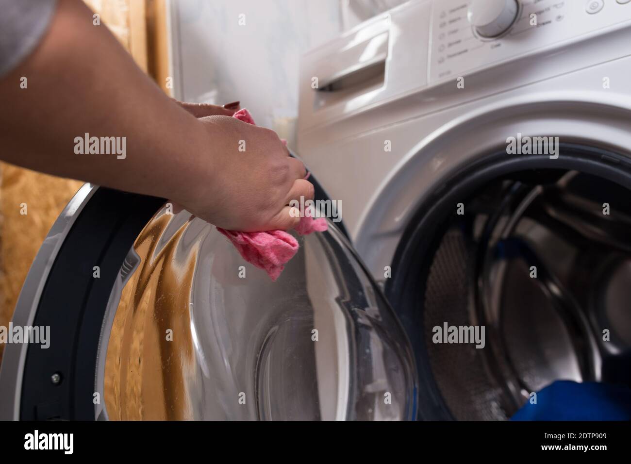 Woman's hands with cloth cleaning a washing machine after washing is ...