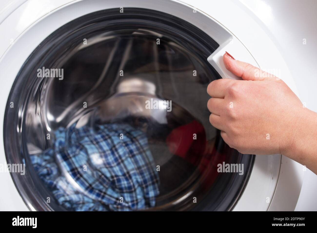 Woman's hand opening door of washing machine in laundry Stock Photo - Alamy