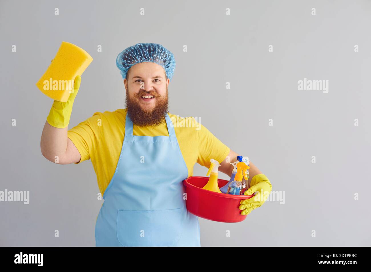 Funny fat man with a beard in an apron washing cleans up on a gray ...