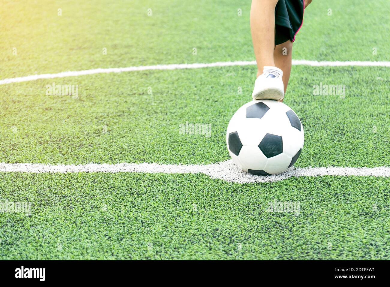 Feet of a boy wearing white sneakers stepping on a soccer ball in the ...