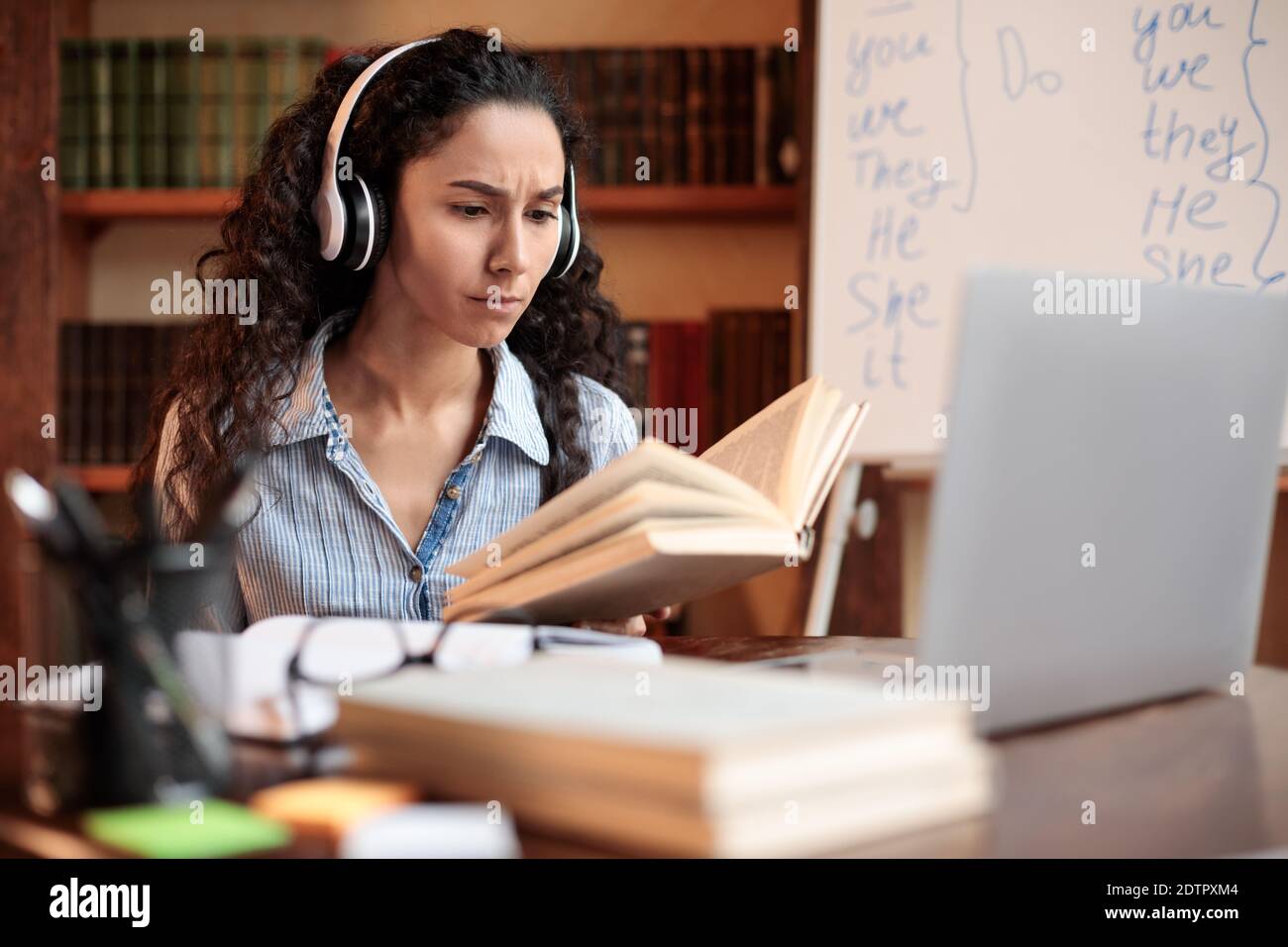 Woman sitting at desk, touching wearing headset, using computer ...