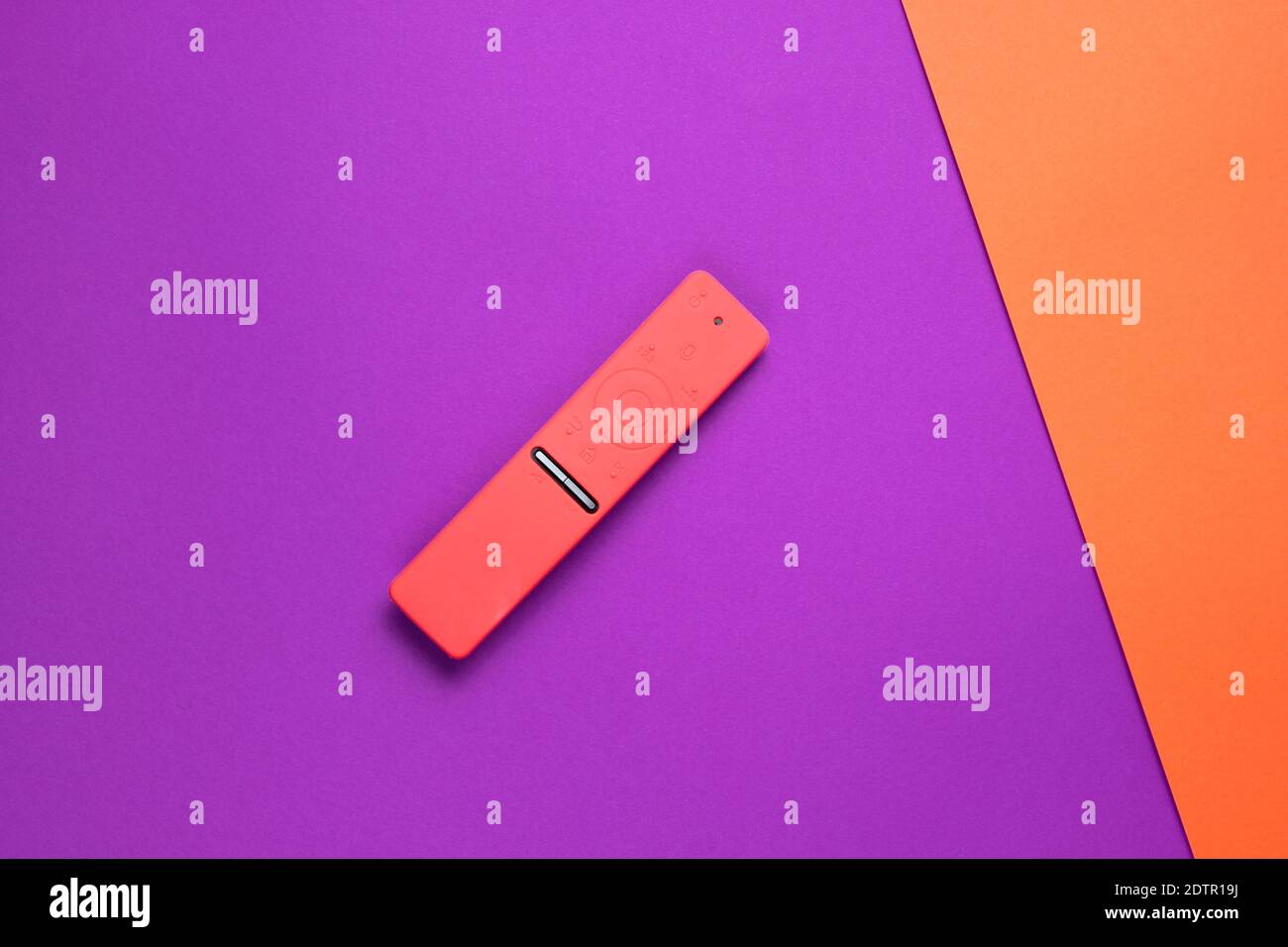 TV remote control in a red silicone case on a purple orange paper ...