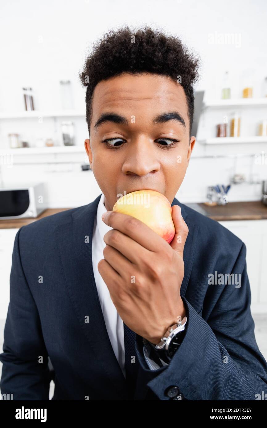curly african american businessman eating fresh apple at home Stock ...