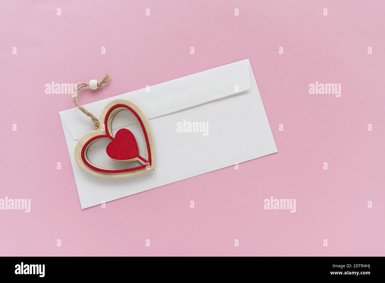 A letter card with a wooden heart on a pink background Stock Photo - Alamy