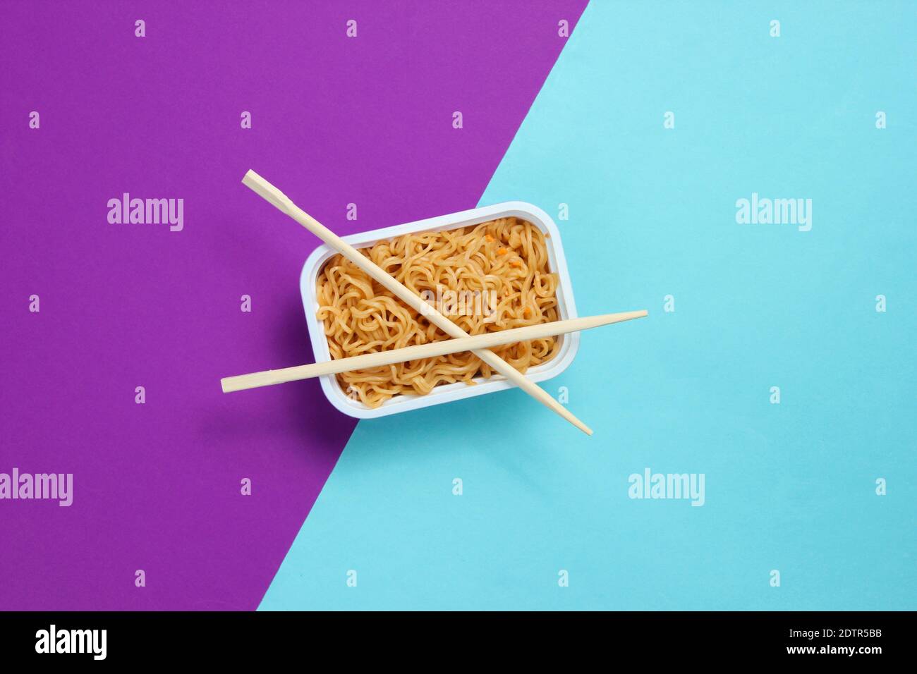 Instant noodles and chinese chopsticks on blue purple background ...