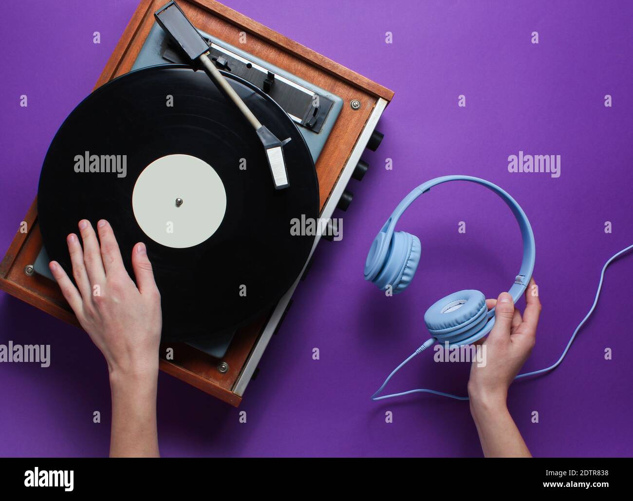 DJ concept. Female hands uses vinyl player and holds the headphones in ...