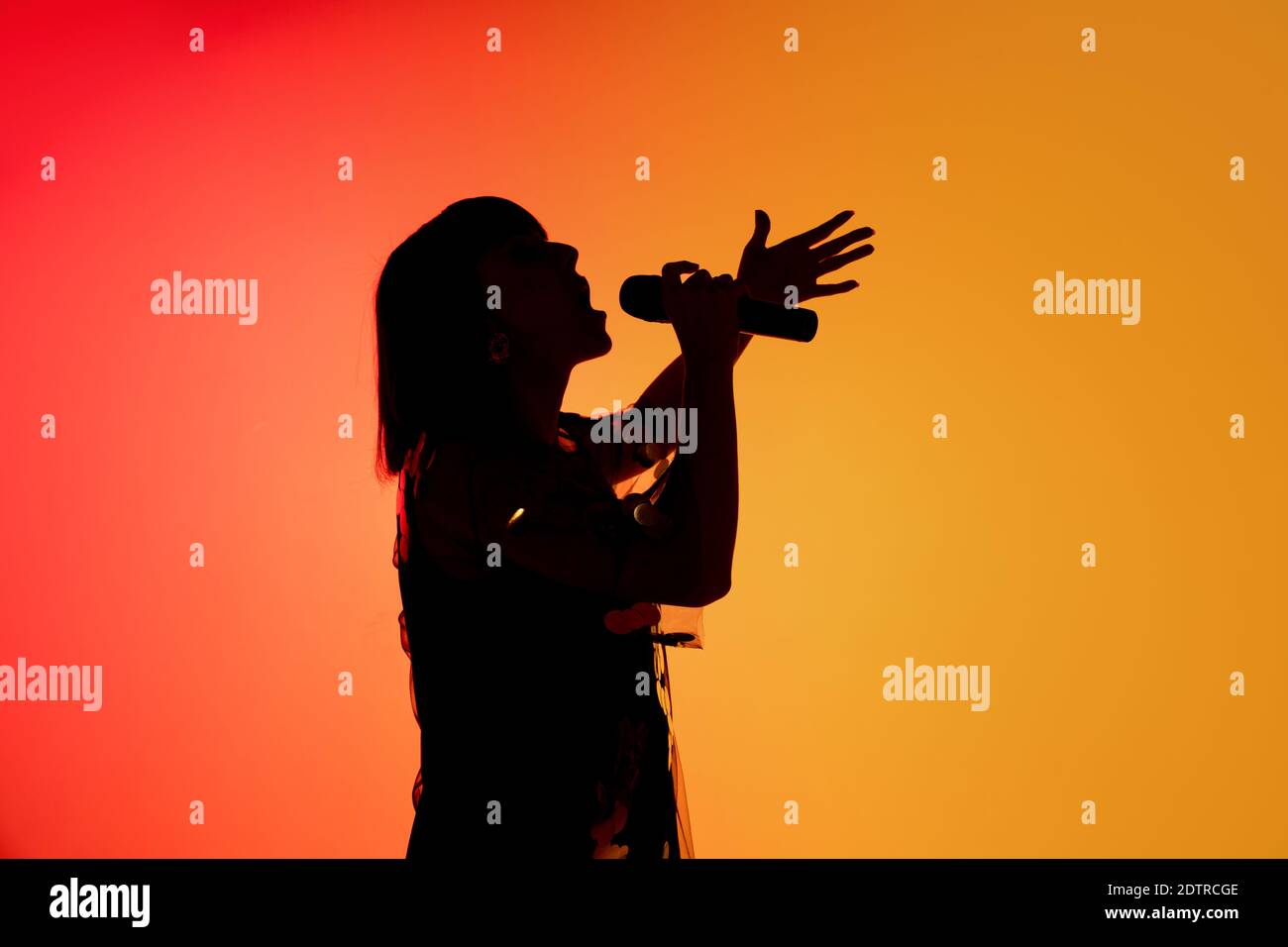 Inspired. Silhouette of young female singer isolated on orange gradient ...