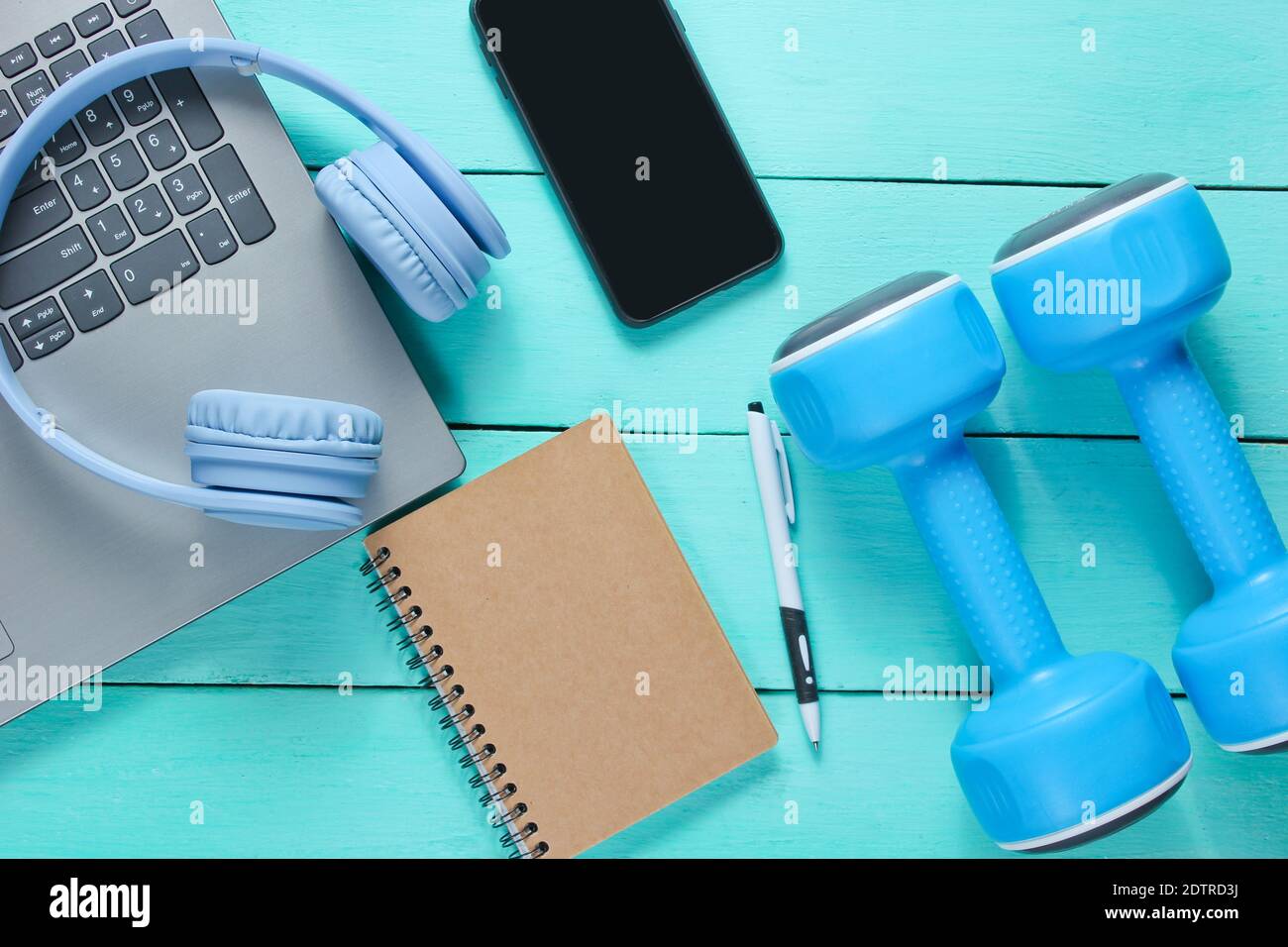 Laptop, headphones, dumbbells, notepad, smartphone on a blue wooden ...