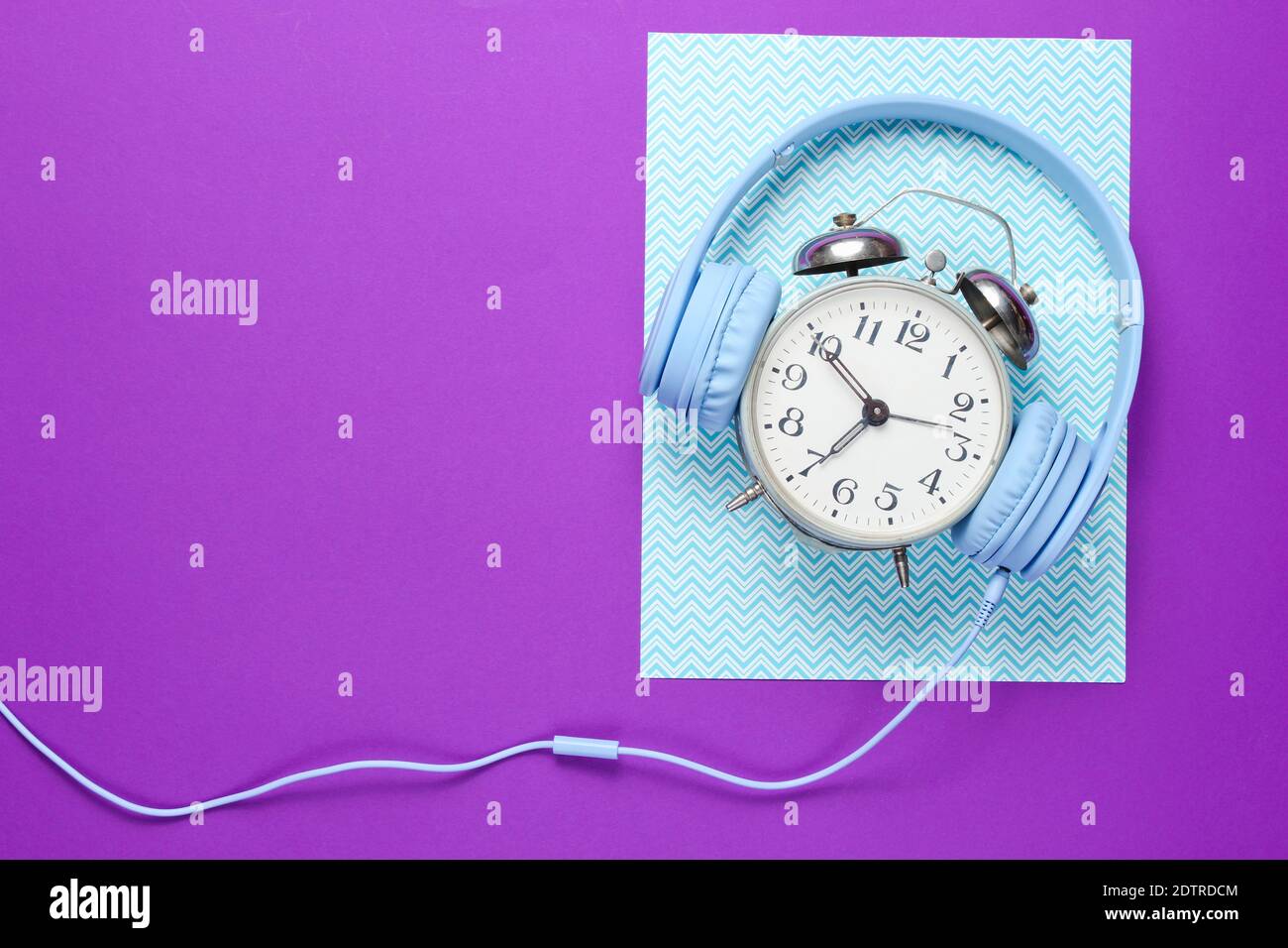 Time listen to music concept. Retro alarm clock with wired headphones ...