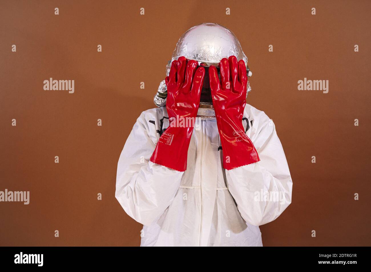 A man wearing Coronavirus protection coverall gloves and shield closing ...
