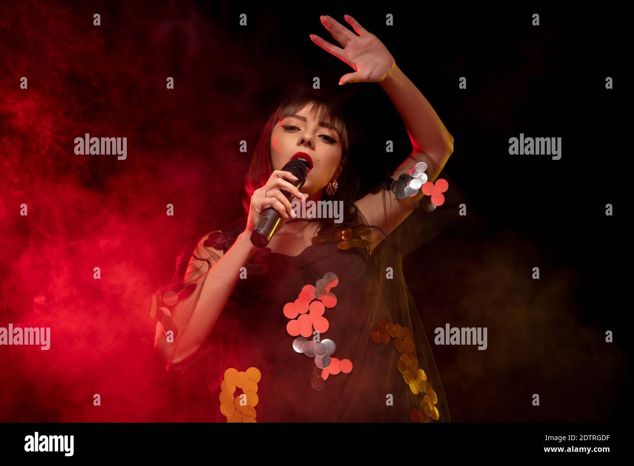 Caucasian female singer portrait isolated on dark studio background in ...