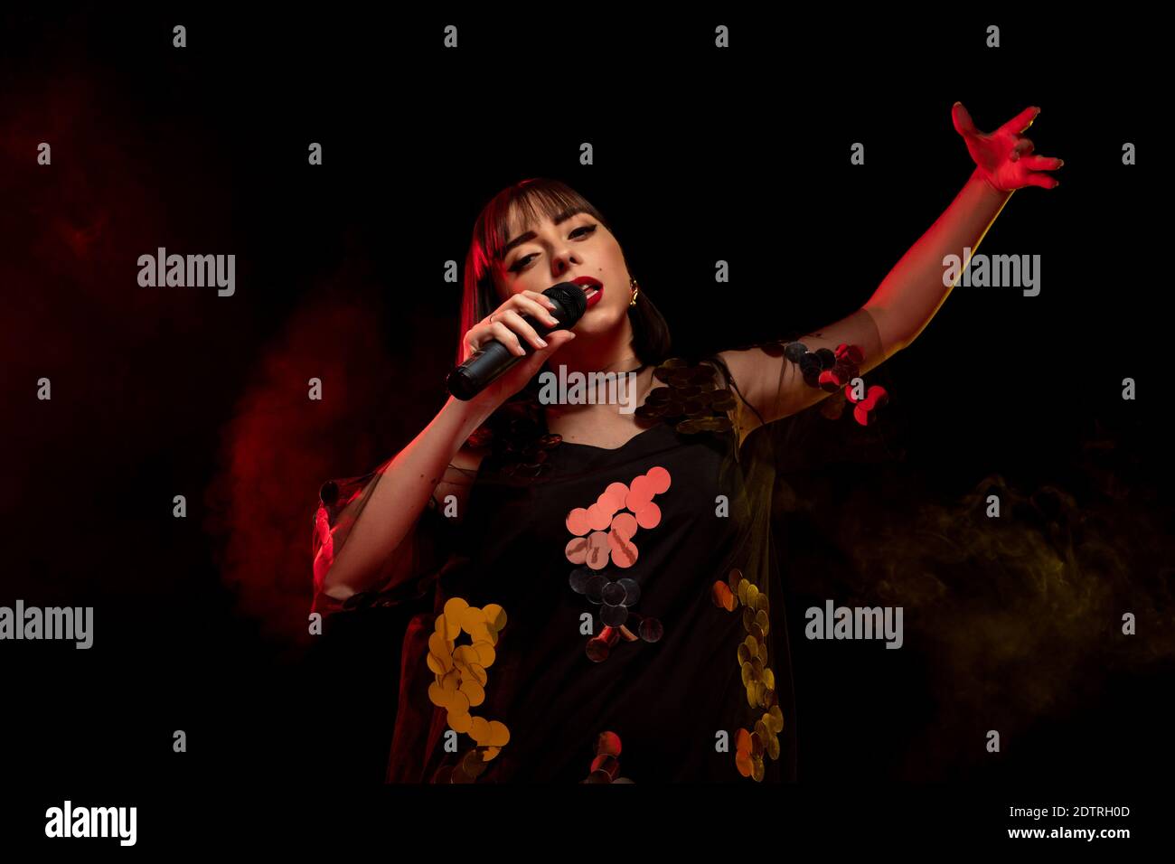 Caucasian female singer portrait isolated on dark studio background in ...