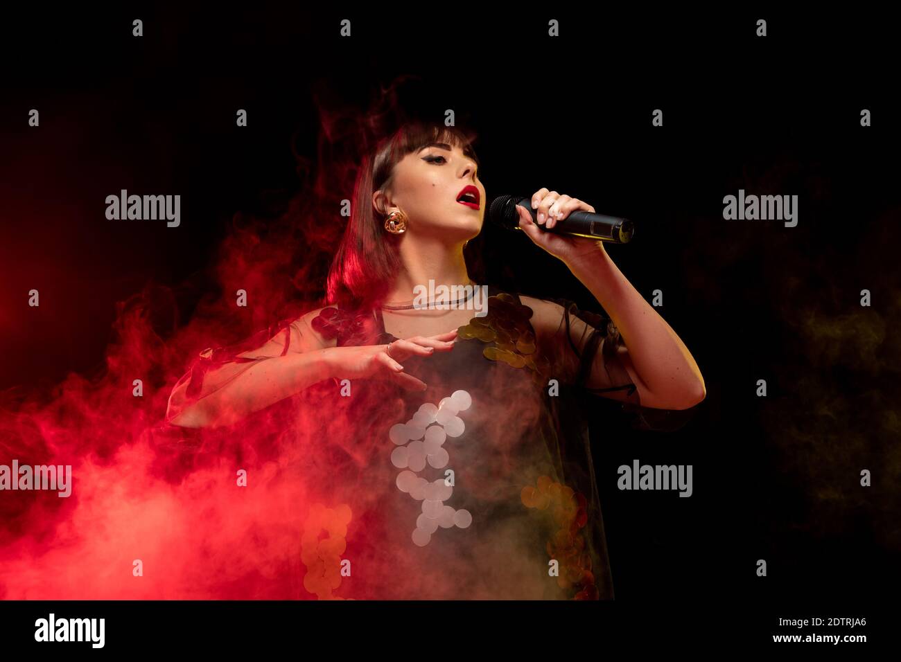 On fire. Caucasian female singer portrait isolated on dark studio ...