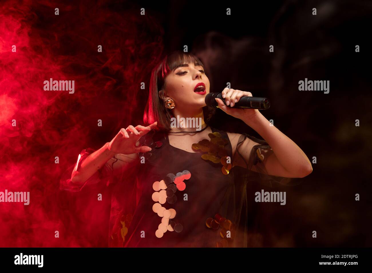 On fire. Caucasian female singer portrait isolated on dark studio ...