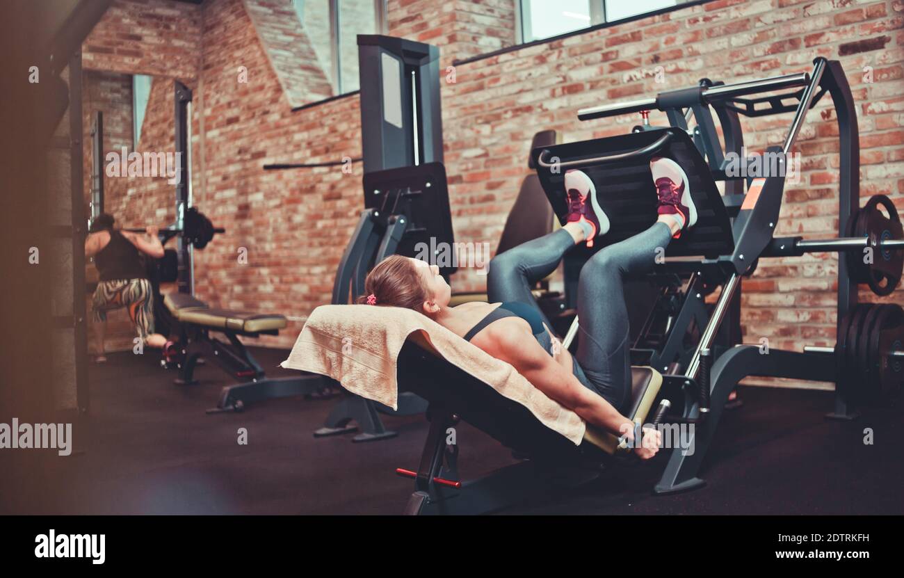 Sportswoman flexing muscles on leg press machine in gym. The training ...