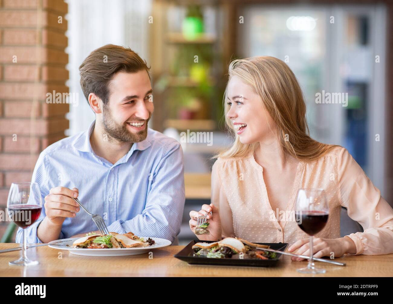 Lovely lady with her boyfriend eating salad and drinking wine ...