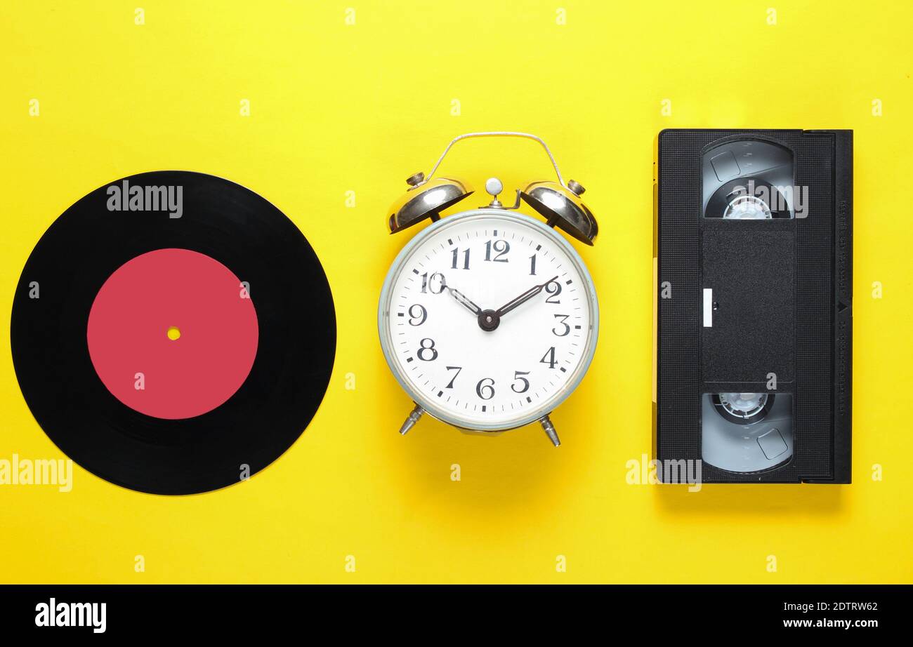 Retro vinyl record, old alarm clock, video tape on a yellow background ...
