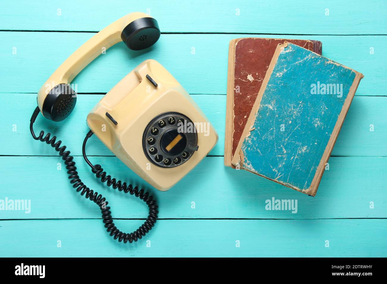Retro rotary telephone and stack of old phone books on a blue wooden ...