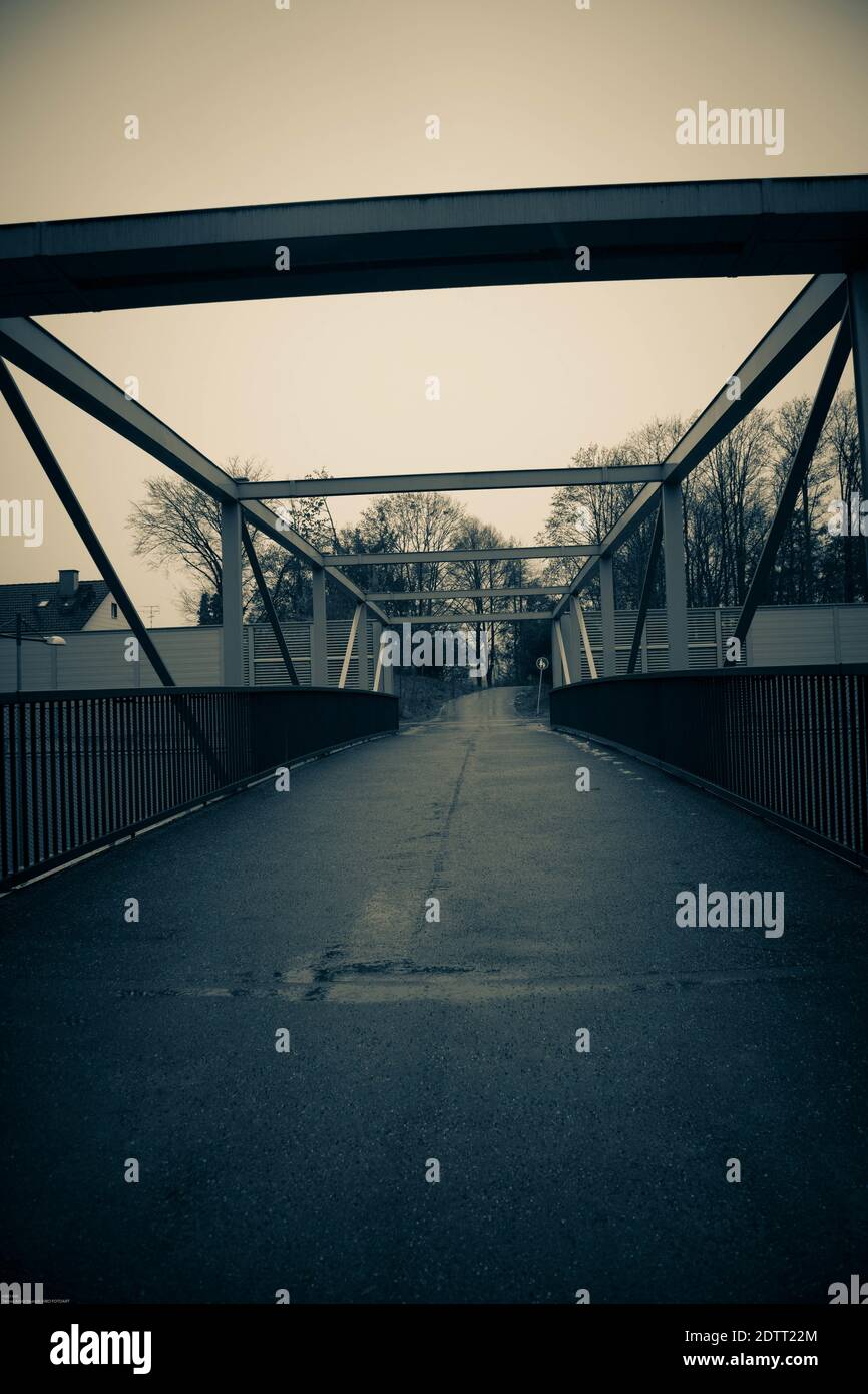A vertical greyscale shot of a bridge captured in the streets of Munich ...