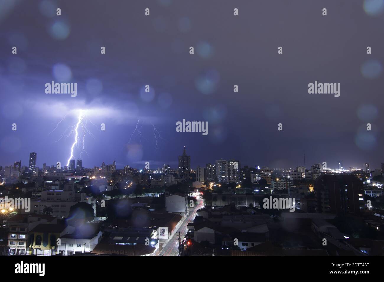 A thunderstorm with lightning in a cloudy sky over the high buildings ...