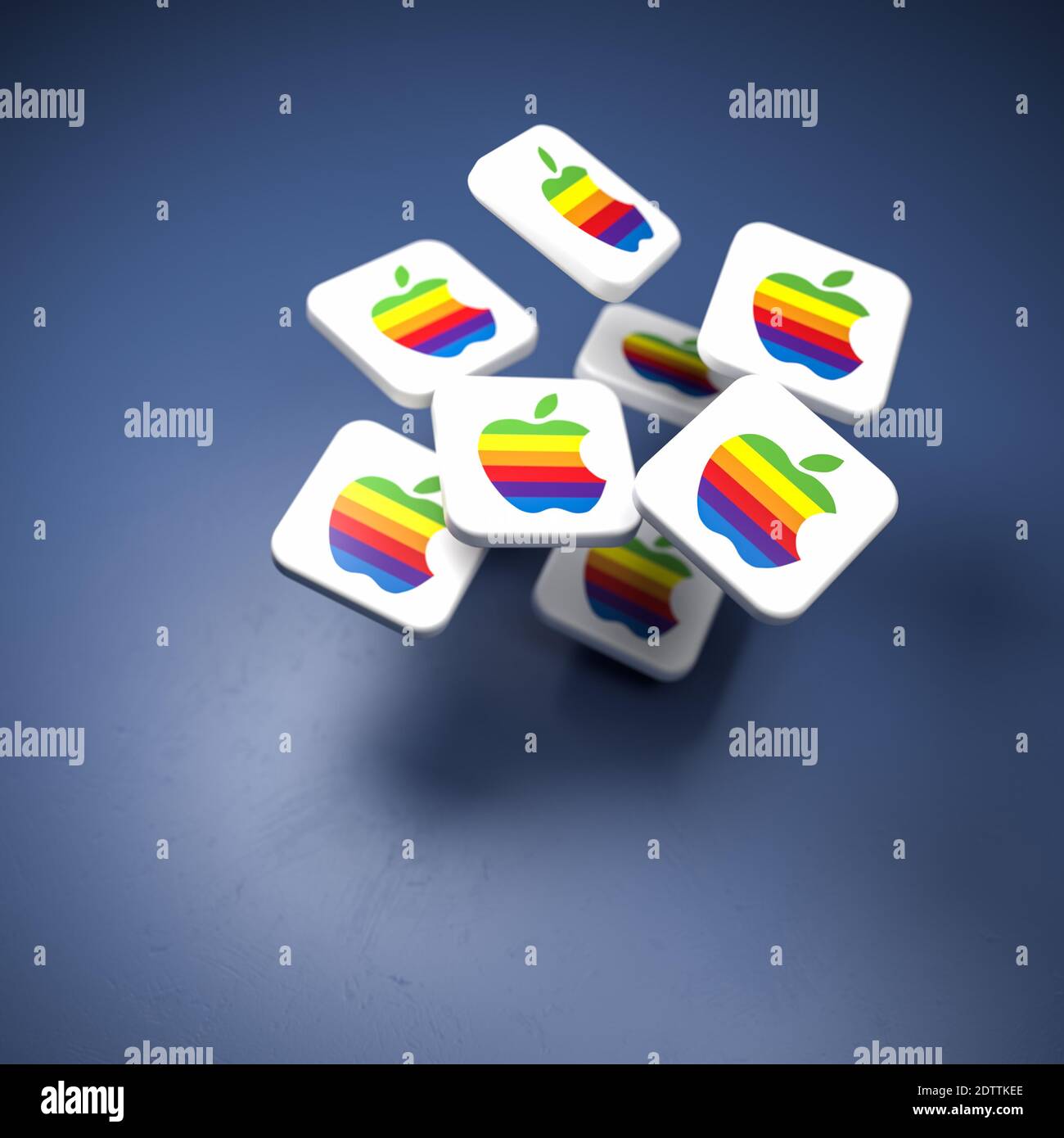 Logos of the company Apple falling onto a blue table. Copy space and ...