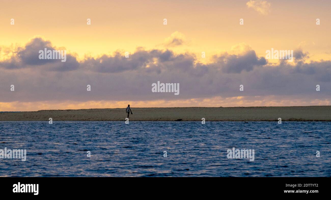 Person walking along mouth of Moore River and Indian Ocean at sunset ...