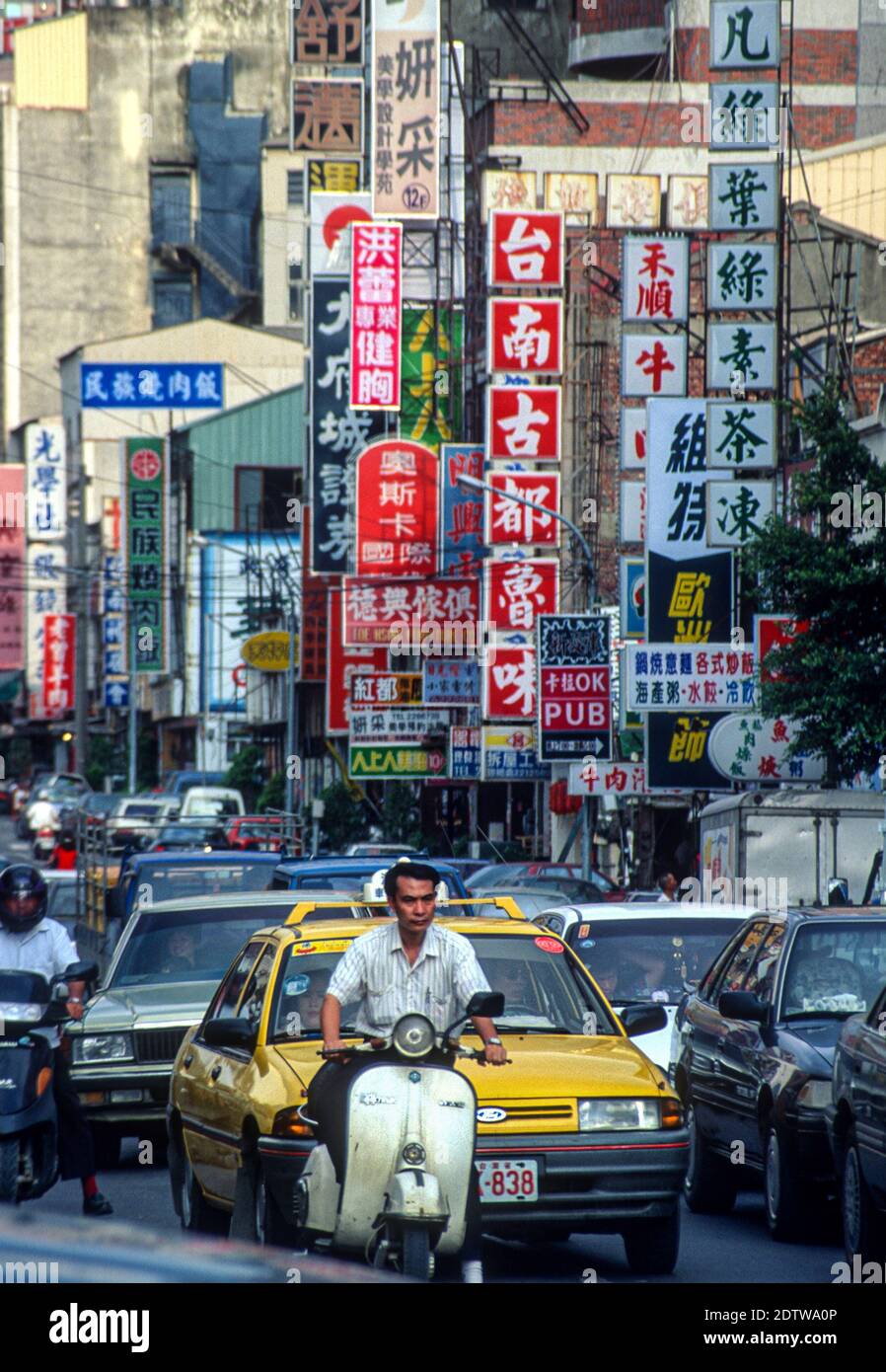 Chinese shop signs and traffic on a busy street, downtown Tainan ...