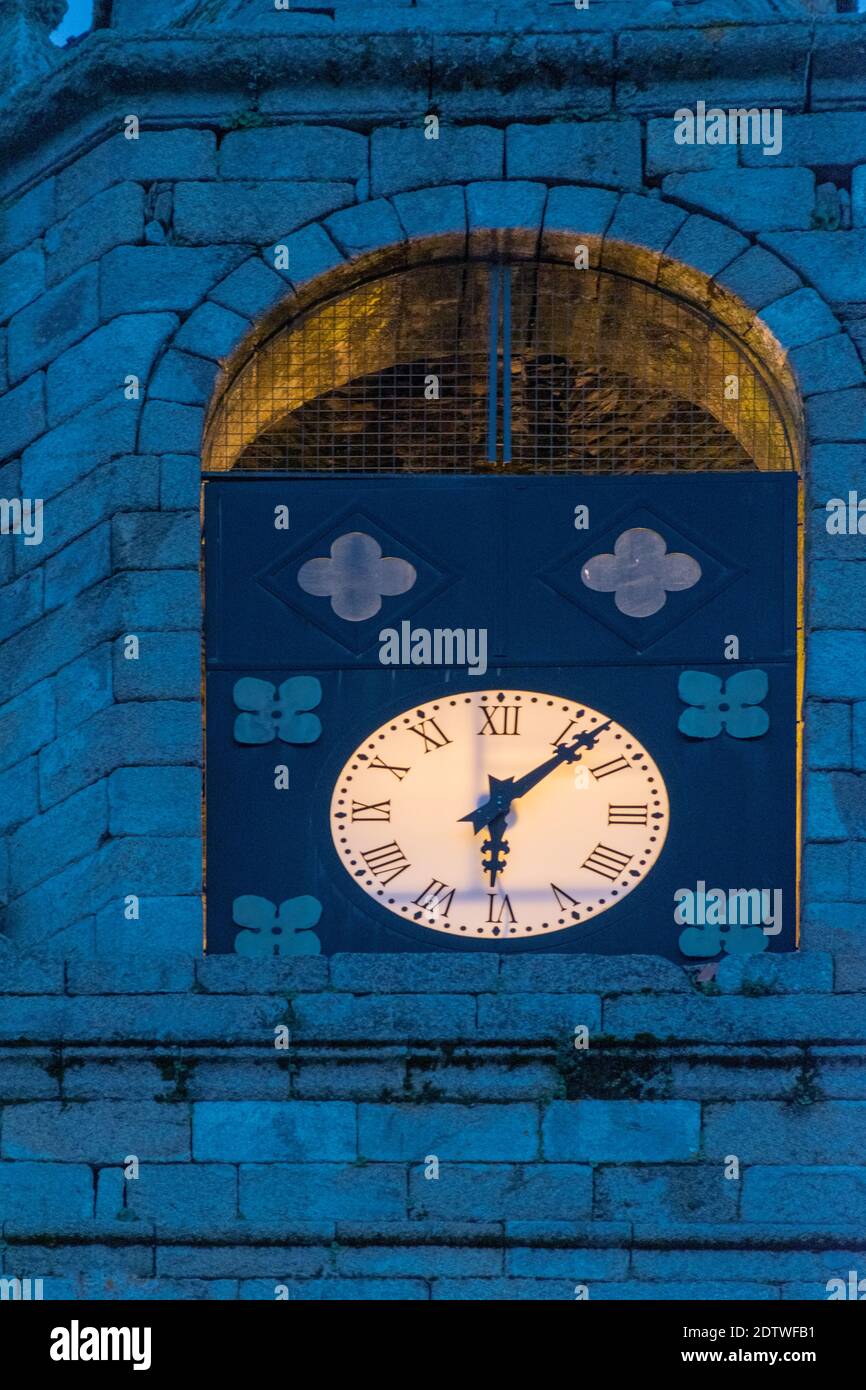 Vertical view of a clock in an illuminated stone tower at night ...