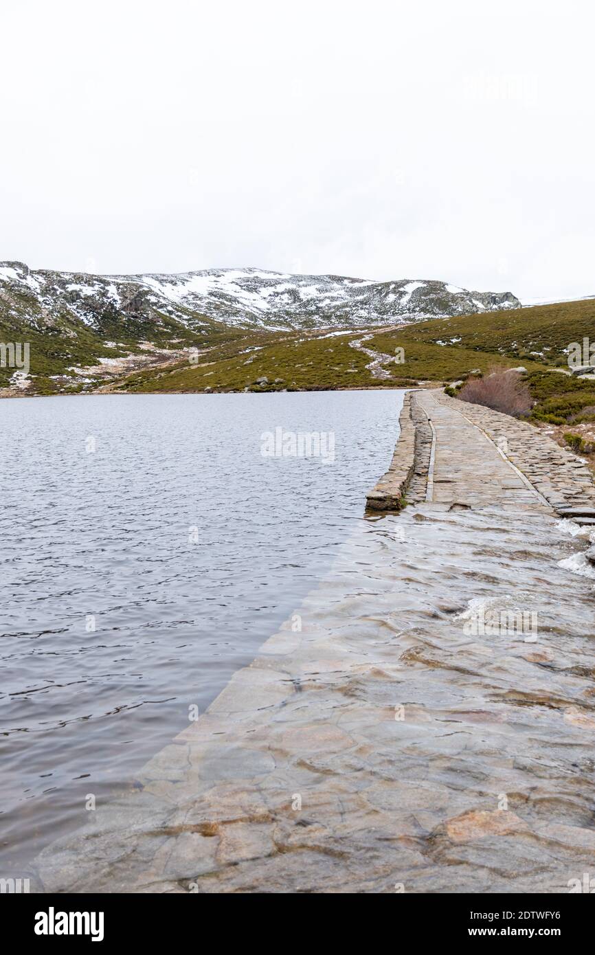 Vertical panoramic image of water overflowing into a dam and stone path ...