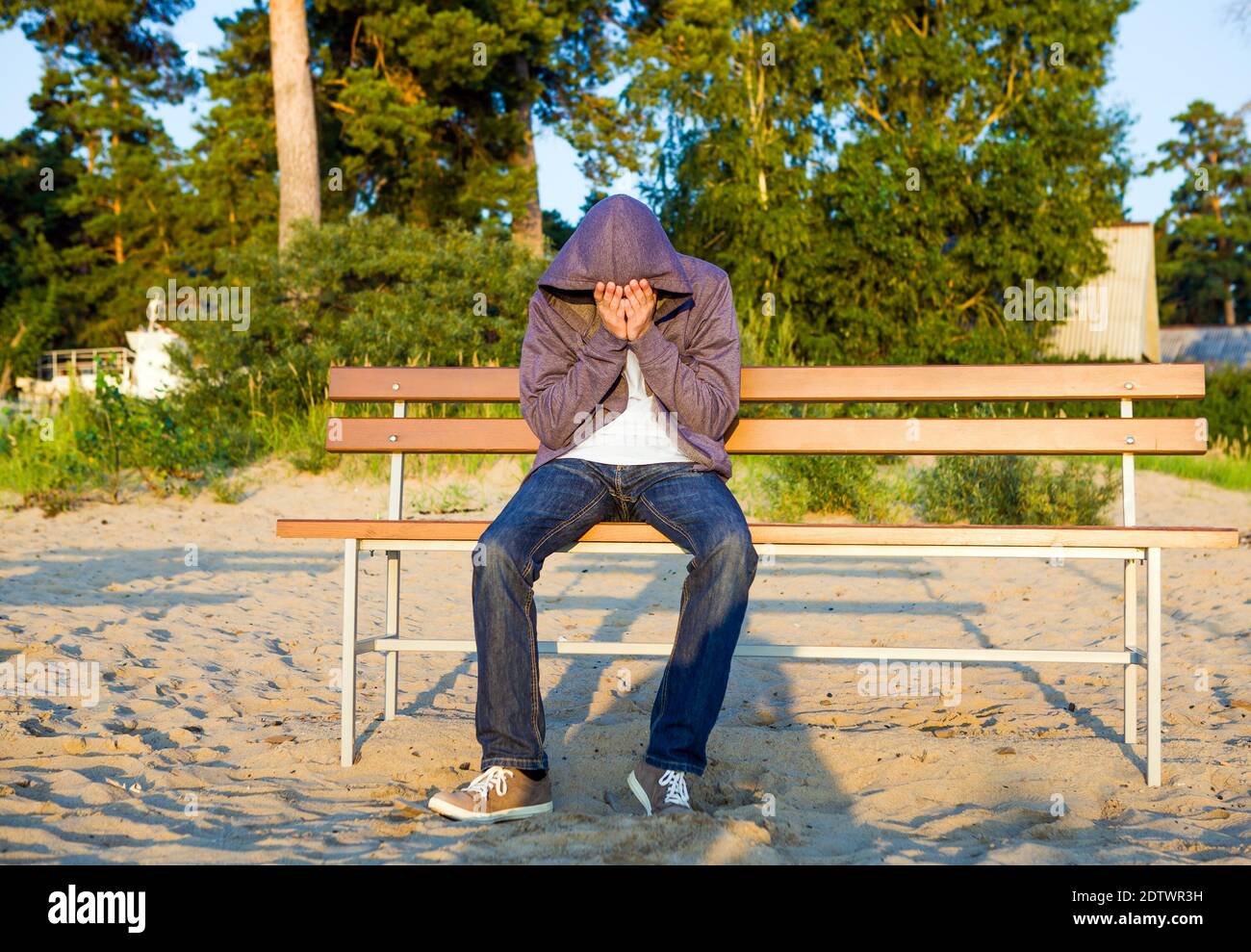 Sad Young Man sit on the Bench outdoor Stock Photo - Alamy