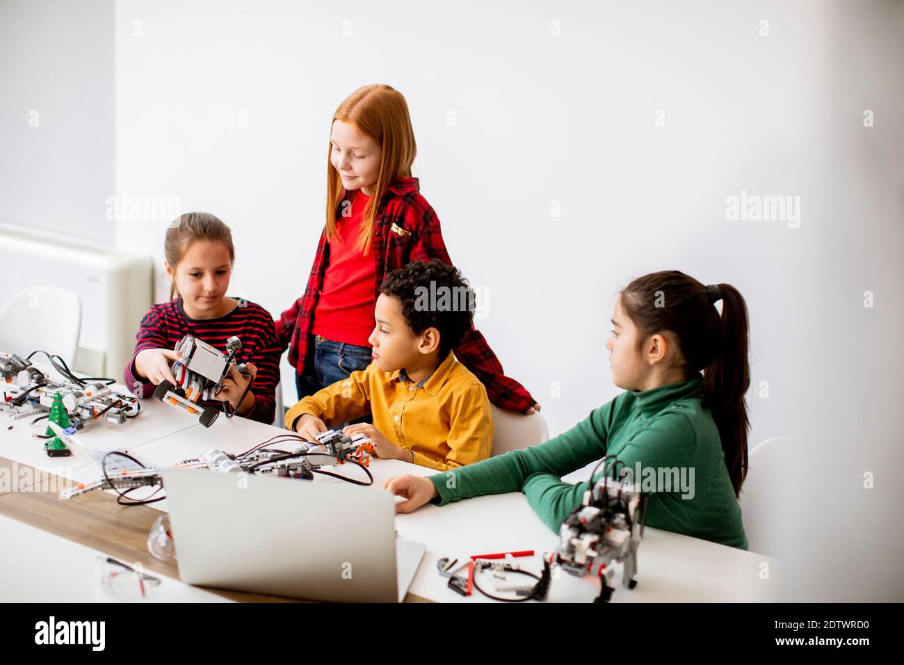 Group of happy kids programming electric toys and robots at robotics ...