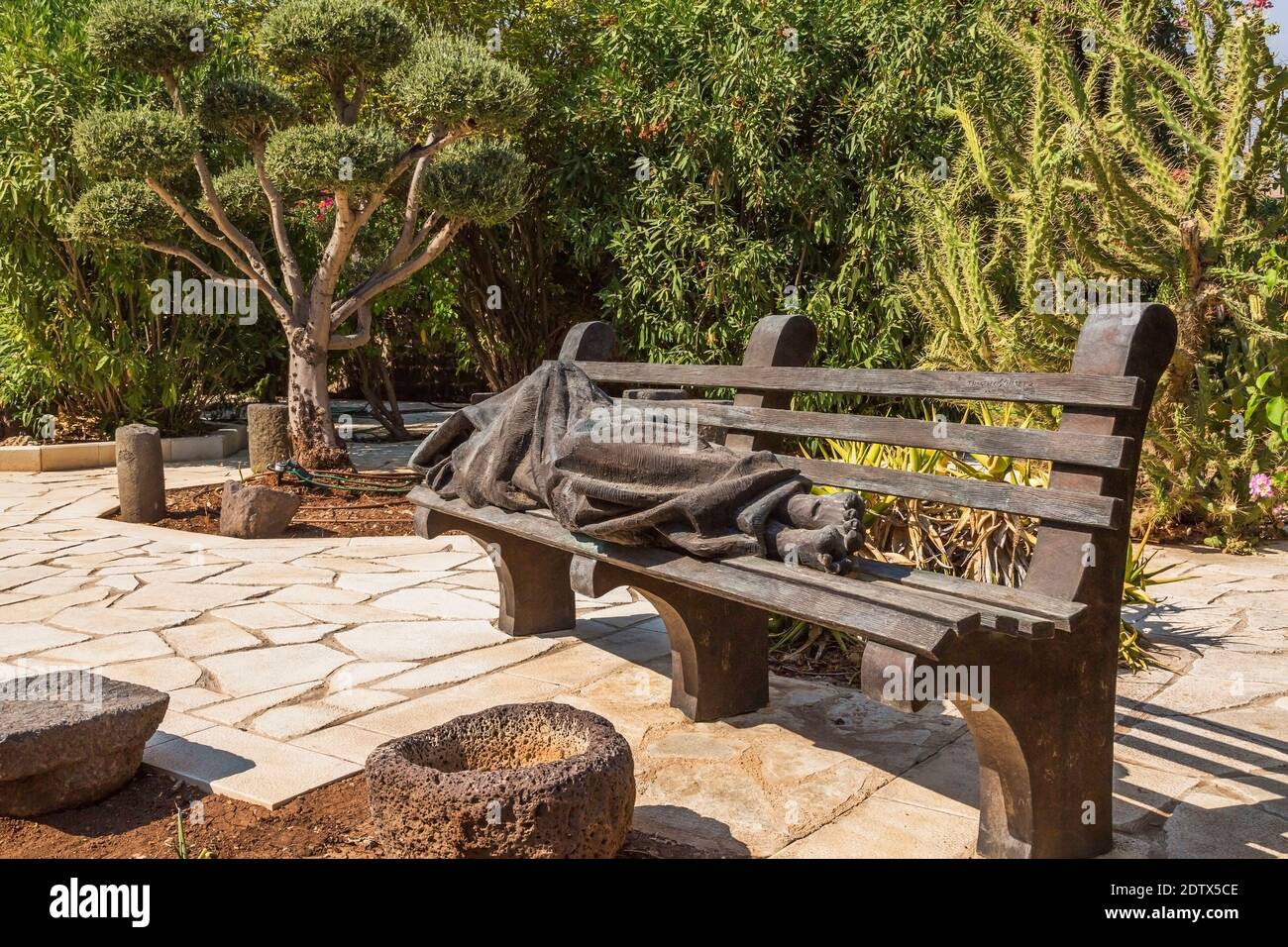 Bronze sculpture of Jesus sleeping on a long bench on the grounds of ...