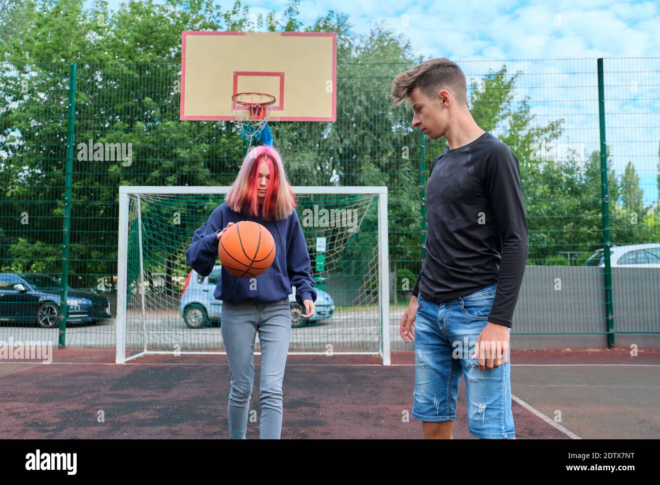 Teenagers guy and girl on an outdoor basketball court playing street ...