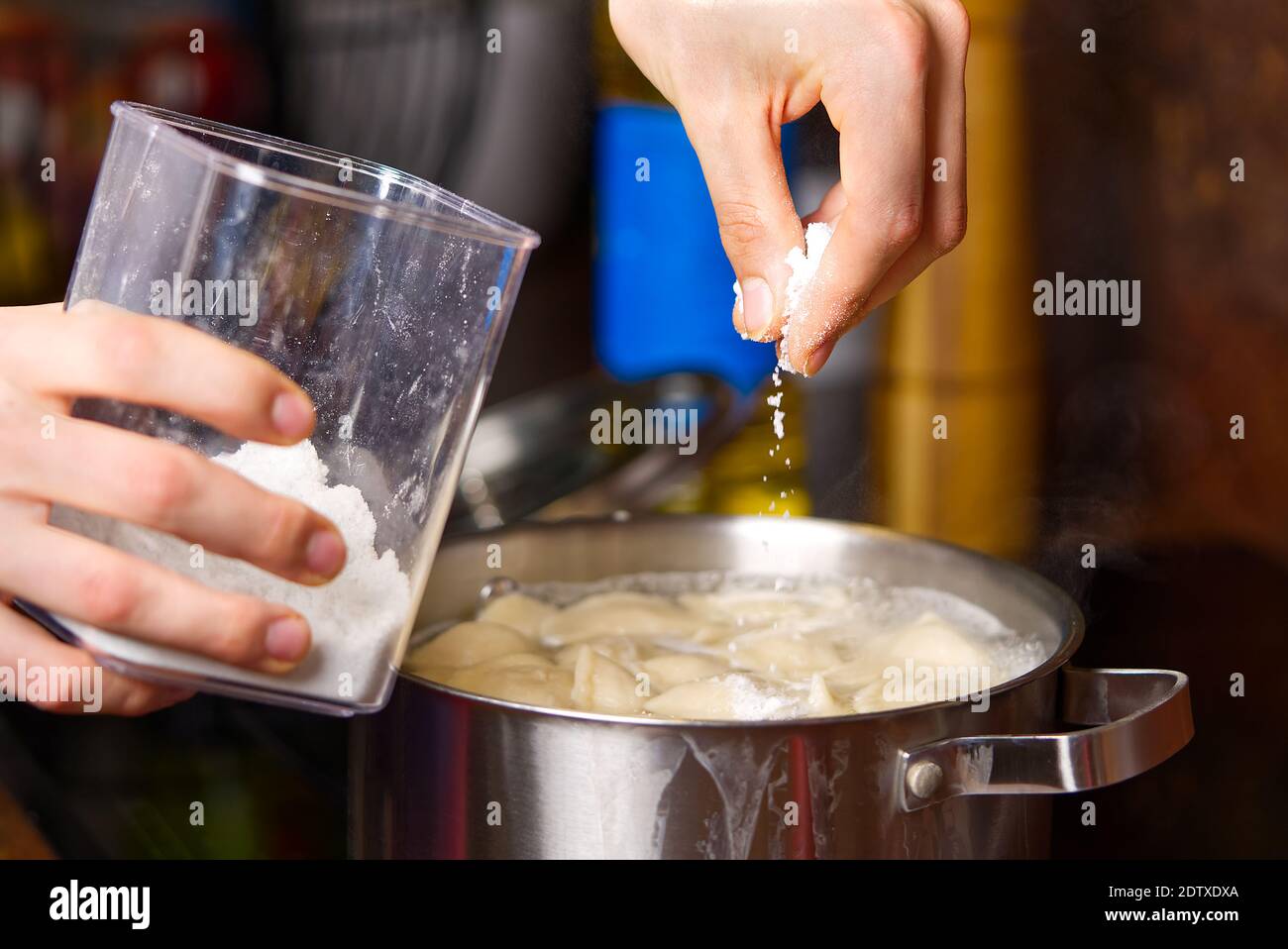 adding salt to a pot of boiling dumplings. Boiled dumplings in a pan ...