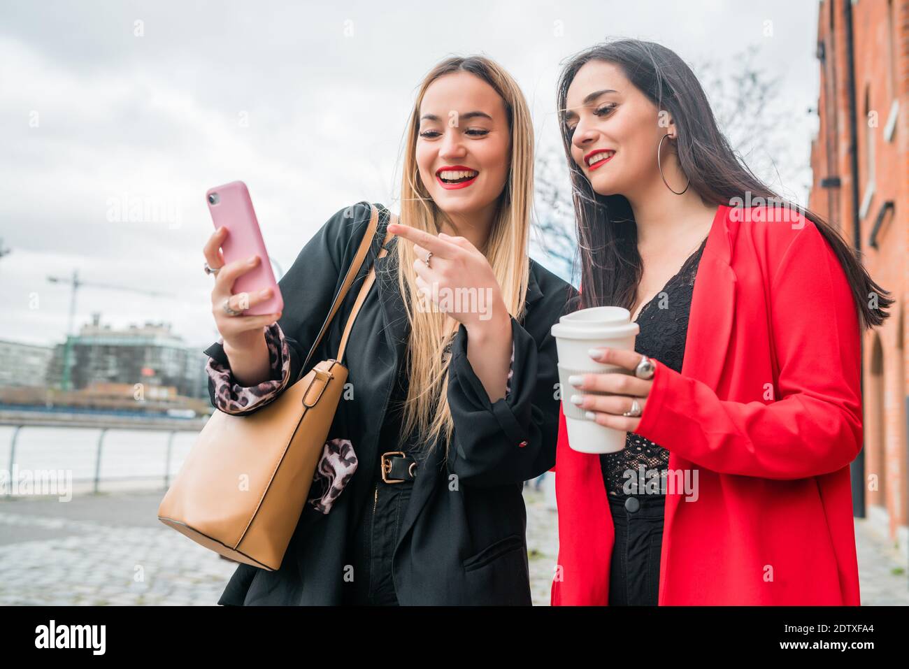 Two young friends using their mobile phone outdoors Stock Photo - Alamy