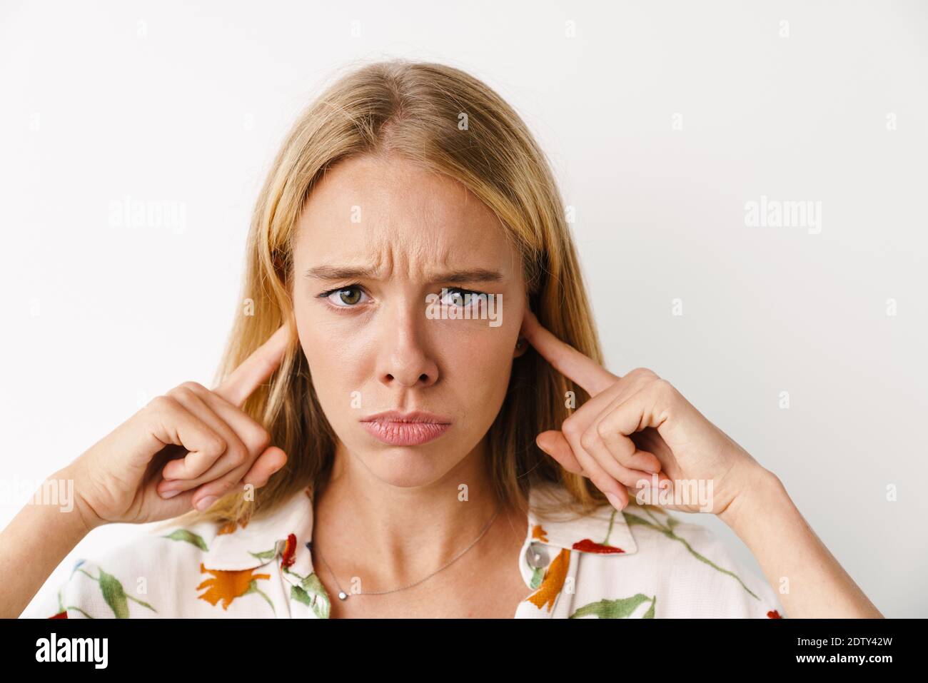 Displeased beautiful girl plugging her ears while posing at camera ...