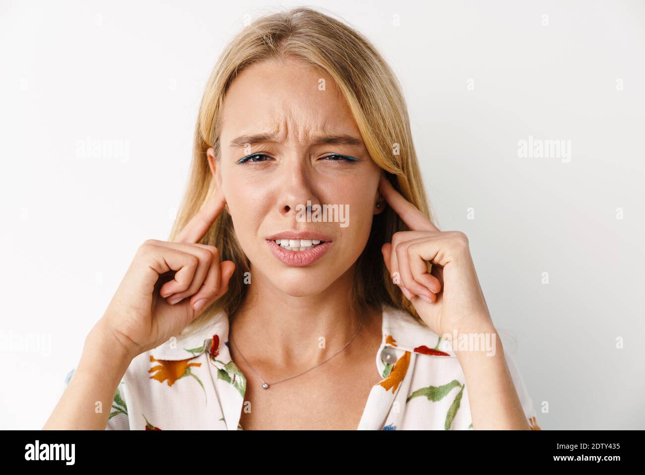 Displeased beautiful girl plugging her ears while posing at camera ...