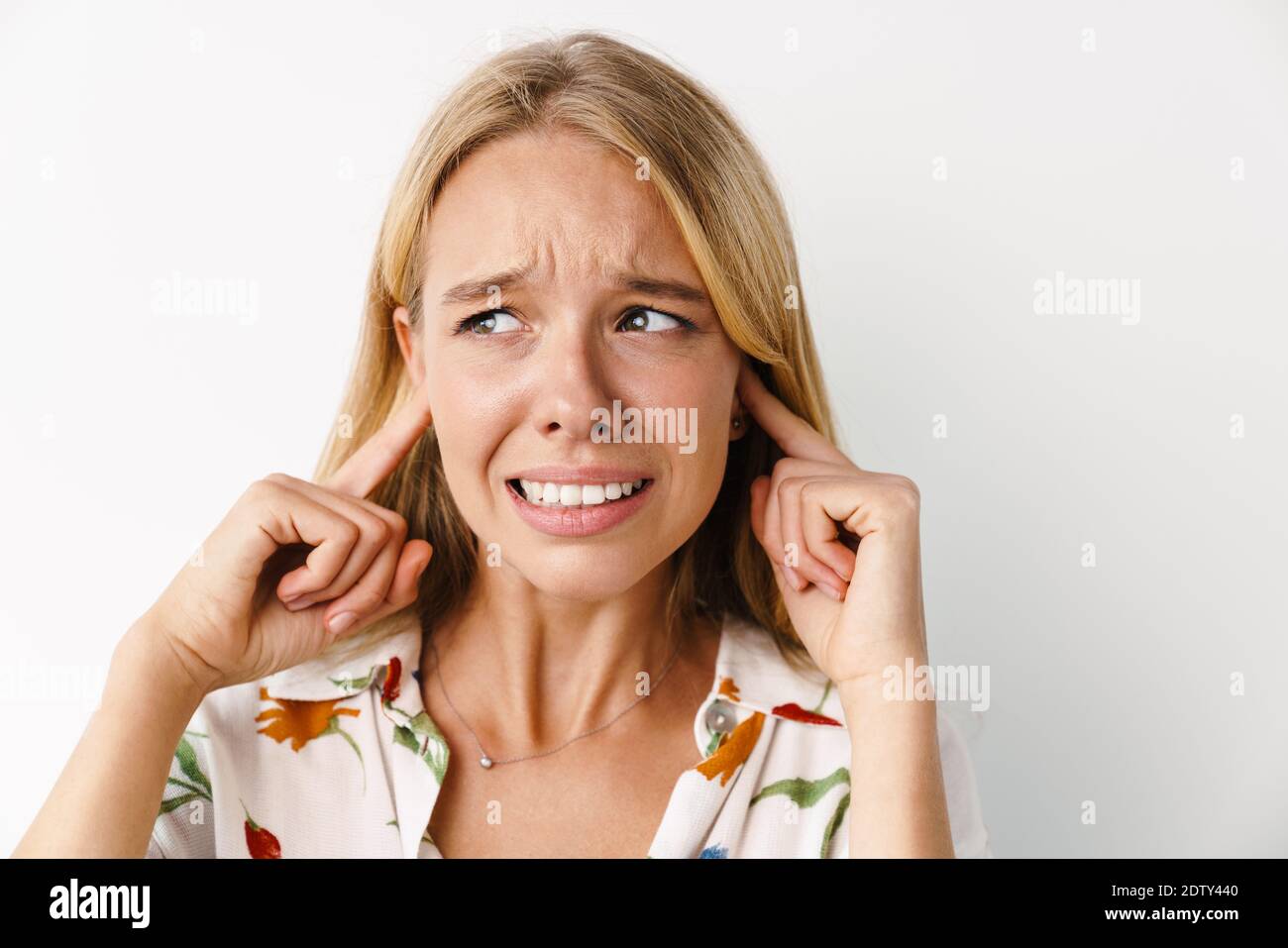 Unhappy beautiful girl plugging her ears while posing at camera ...