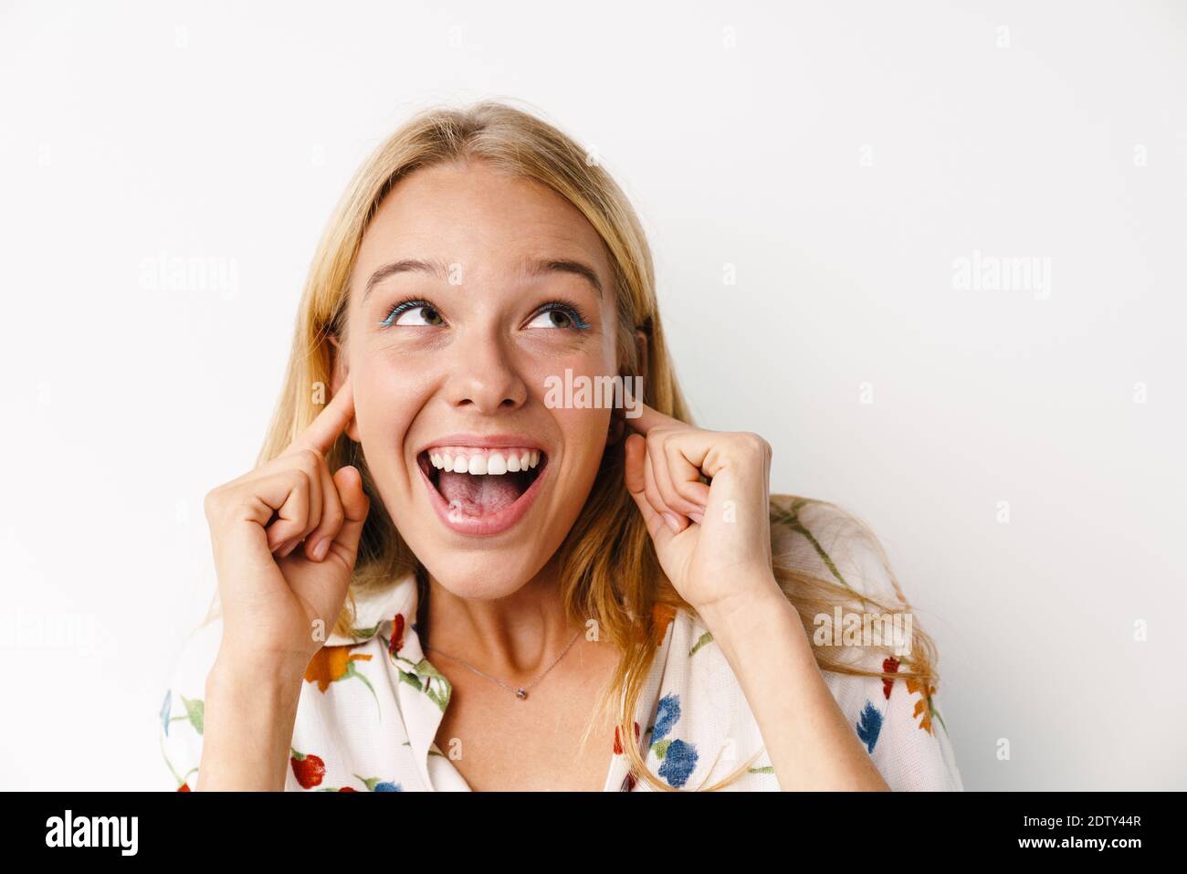 Laughing beautiful girl plugging her ears while posing at camera ...