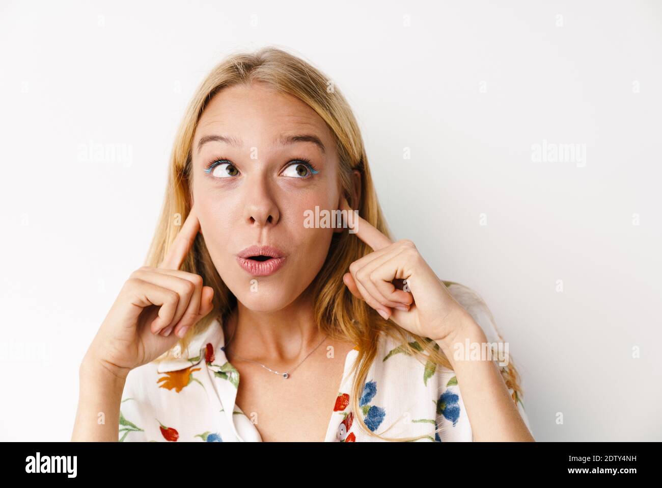 Surprised beautiful girl plugging her ears while posing at camera ...