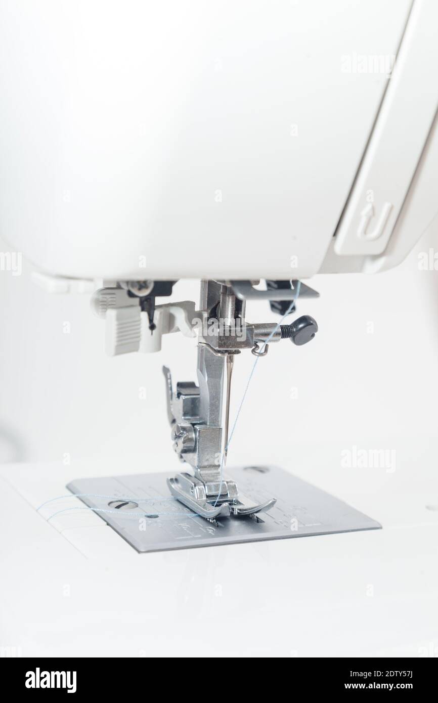 Vertical closeup of sewing machine needle against white background ...